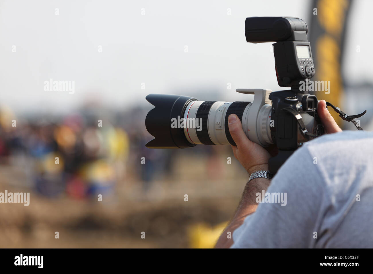 Detail of a photographer's hands holding a DSRL camera with a long zoom ...