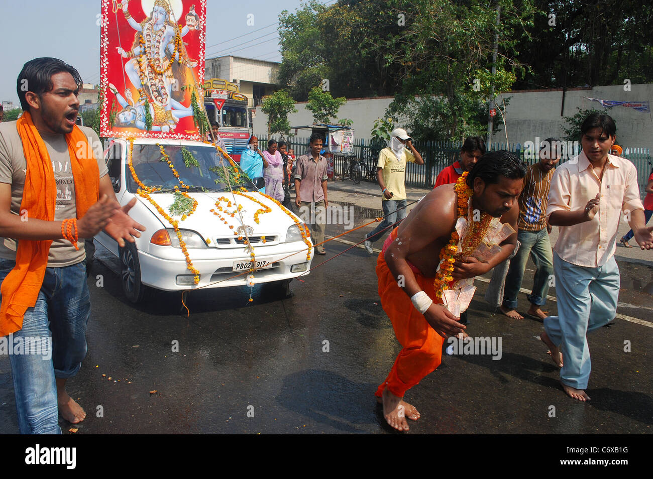 A devotee of Devi Maha Mariamman pulls a car with ropes hooked to his ...