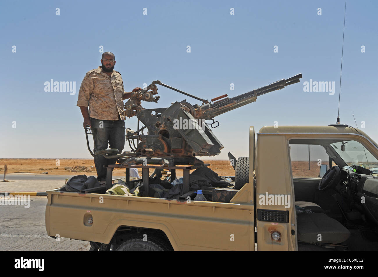 a NTC fighter stands next to his AAgun on the back of a pick up truck ...