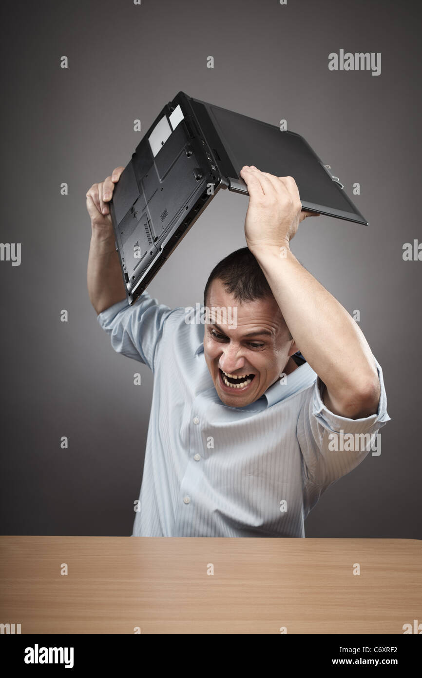 Extremely angry businessman smashing his laptop on the desk Stock Photo ...