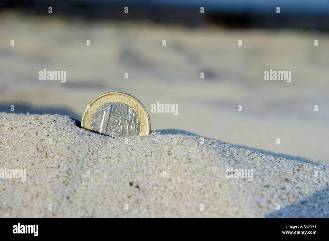 Euro coin in the sand, lost money Stock Photo - Alamy