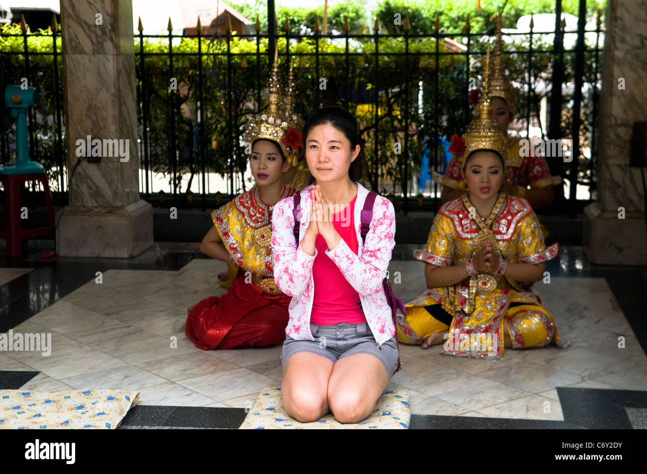 A Thai Woman Praying In A Local Temple She Is Accompanied By