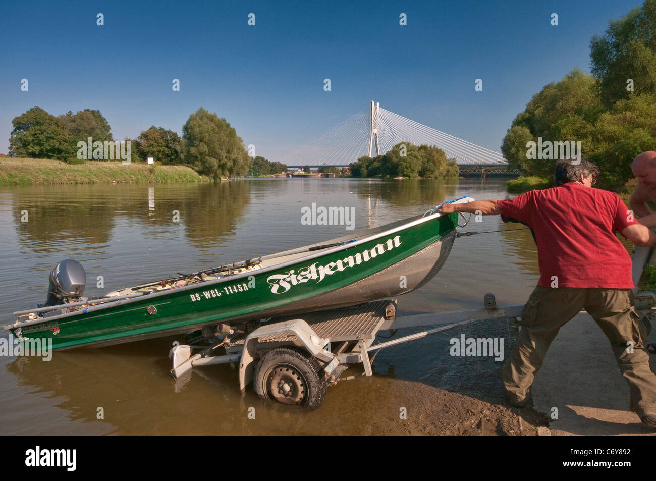 Men loading boat on trailer at Oder river near Redzinski Bridge in ...
