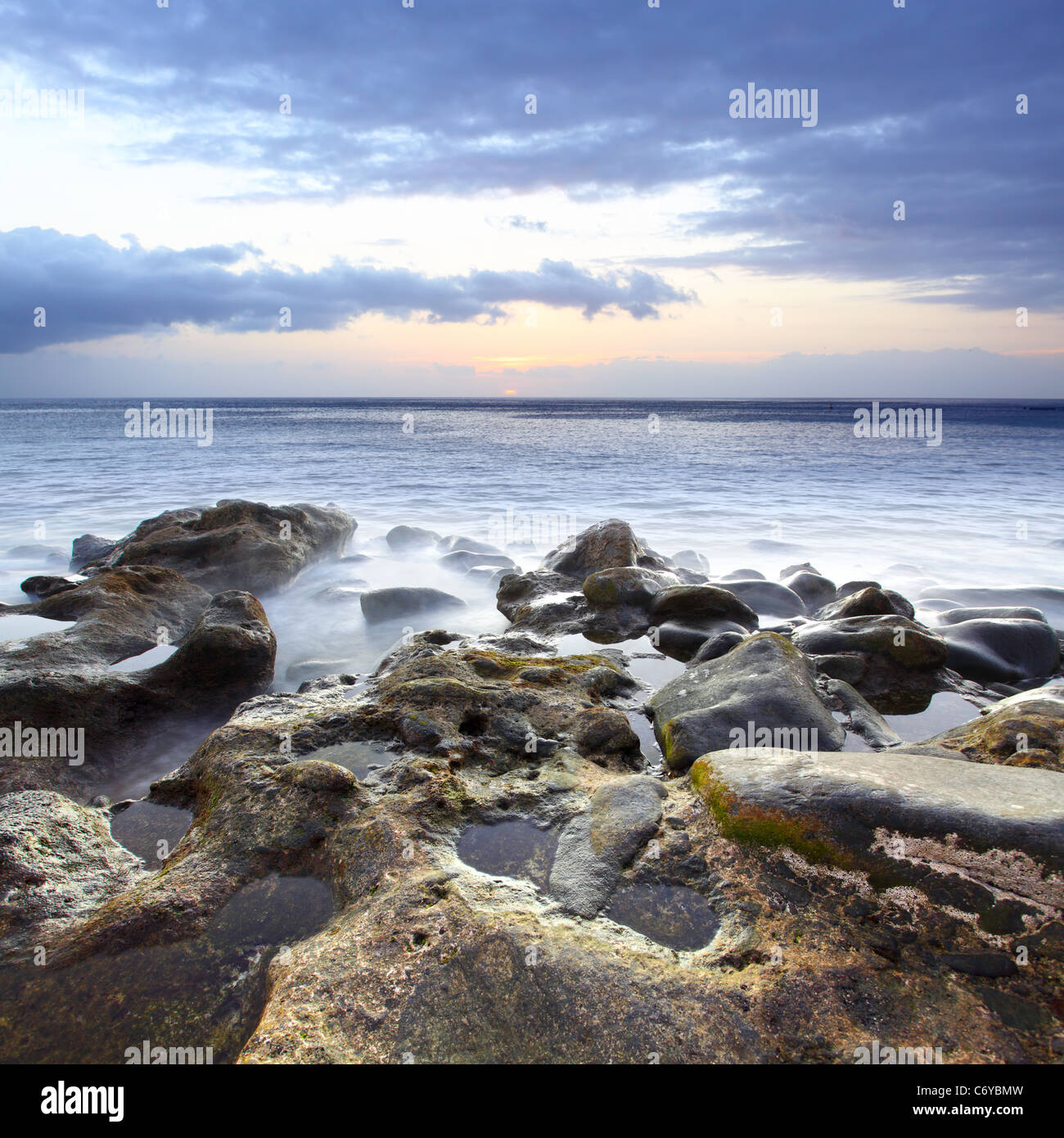 Beautiful sundown at rocky beach. Water in motion blur Stock Photo - Alamy
