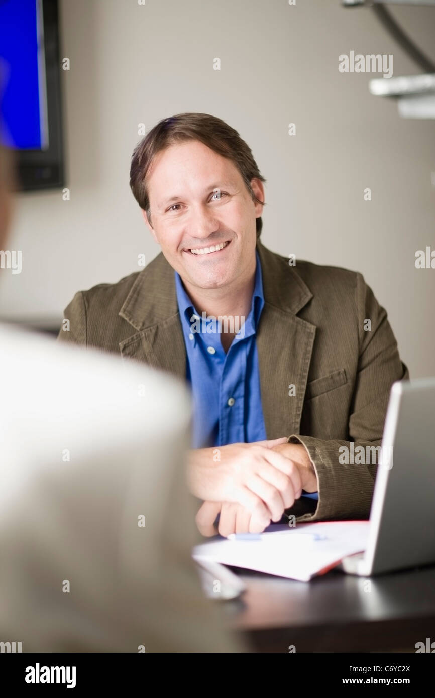 Businessman smiling at desk in office Stock Photo - Alamy