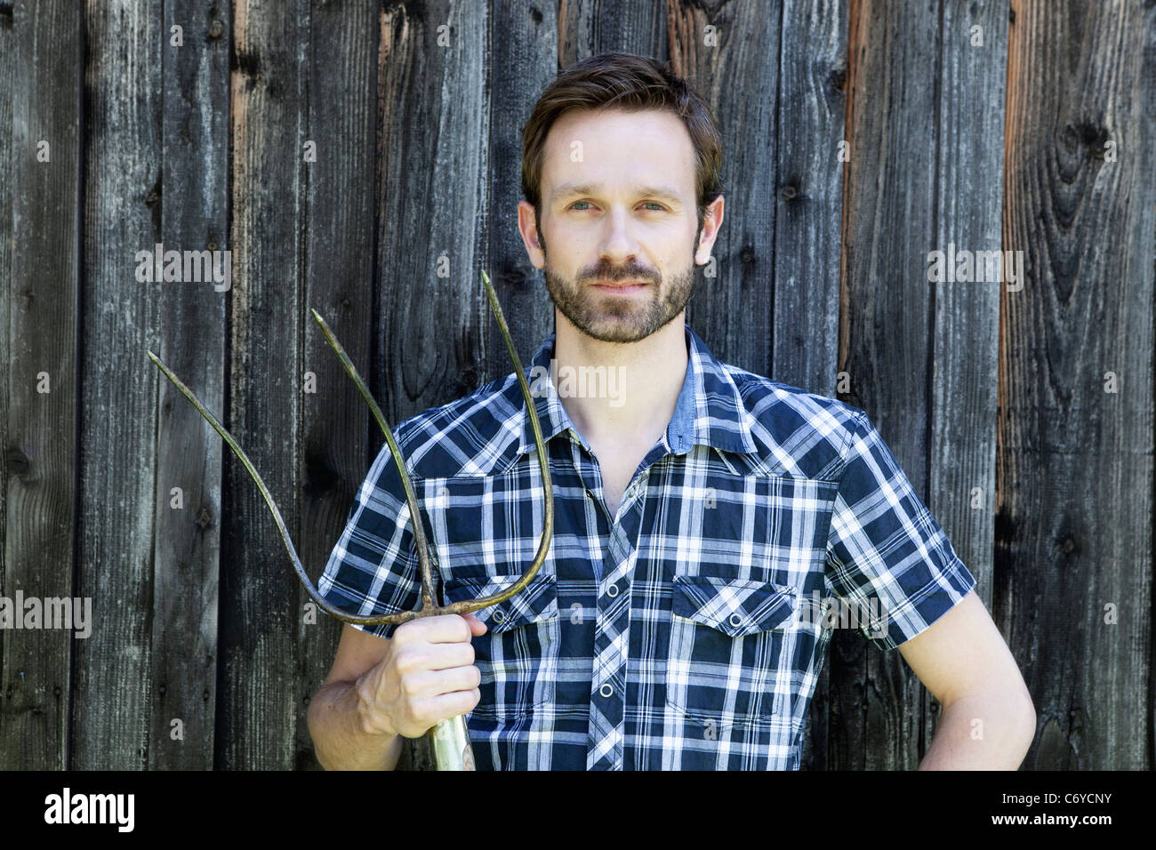 Man holding rake outdoors Stock Photo - Alamy