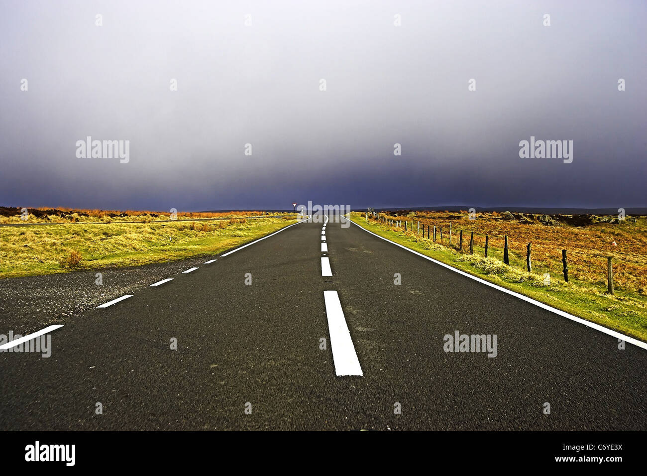 Straight road leading off into the distance with fields either side and ...