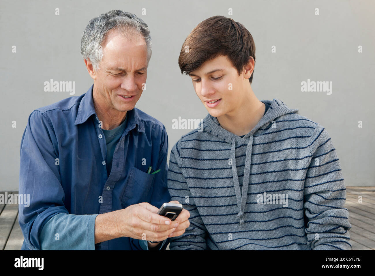 Father and son using cell phone together Stock Photo - Alamy