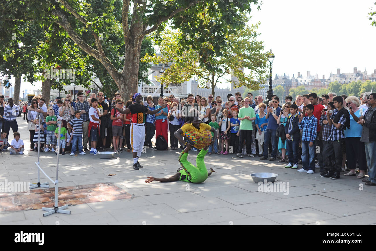 Acrobat buskers performing to crowds on the South Bank in London city ...
