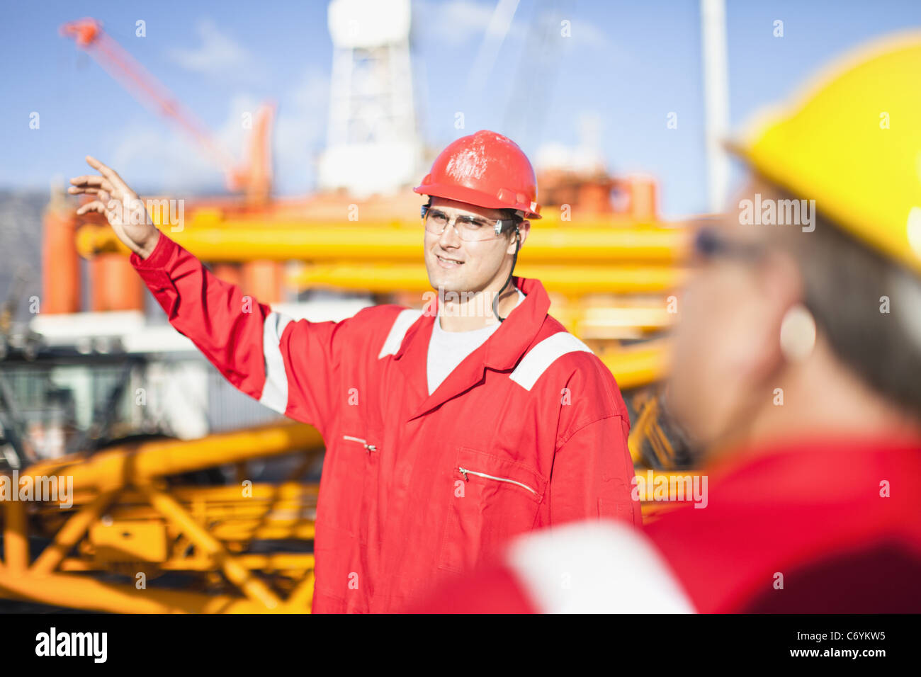Workers talking on oil rig Stock Photo - Alamy