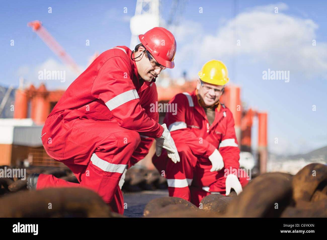 Workers on oil rig examining chains Stock Photo - Alamy