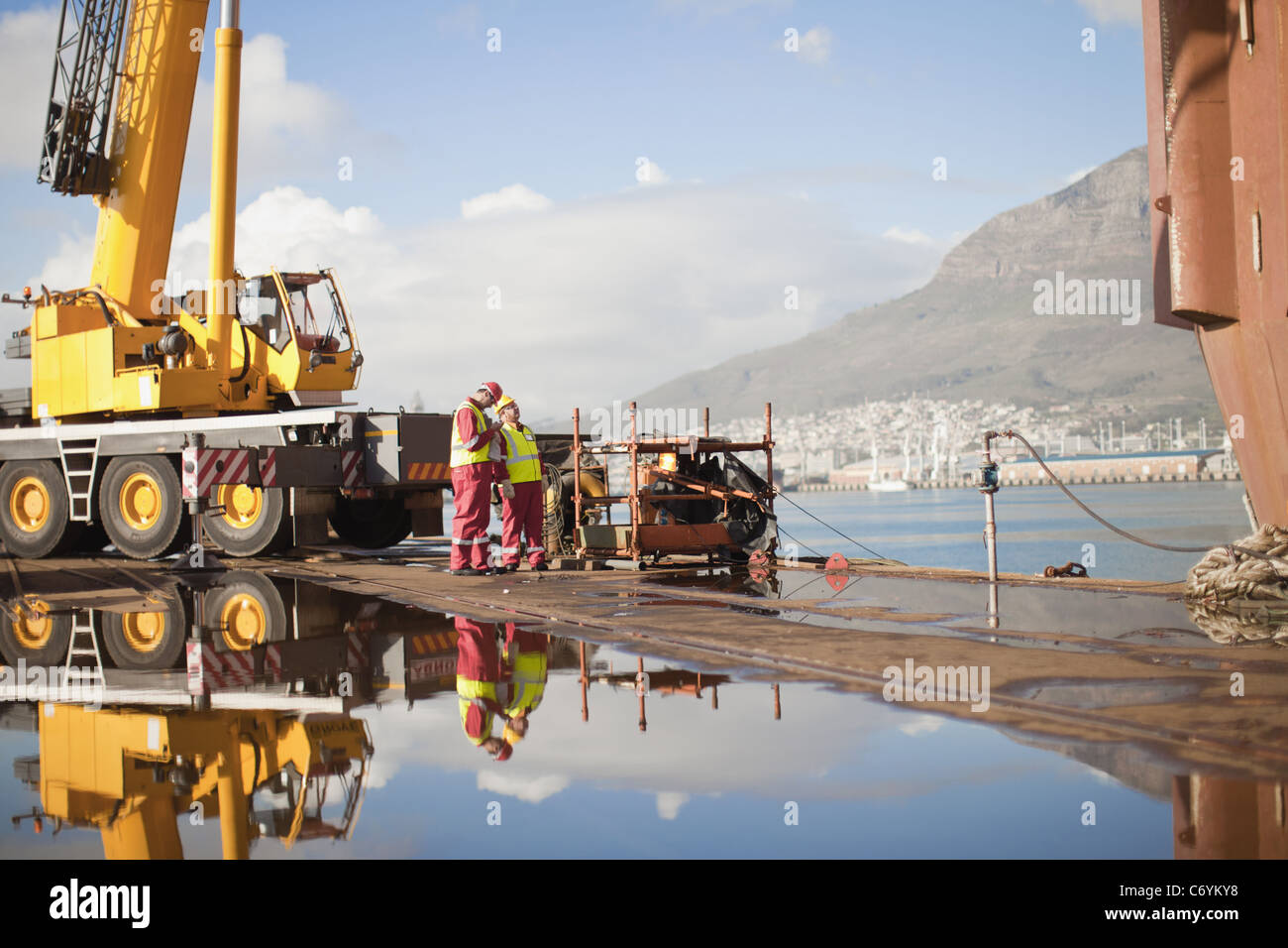 Workers on oil rig standing by crane Stock Photo - Alamy