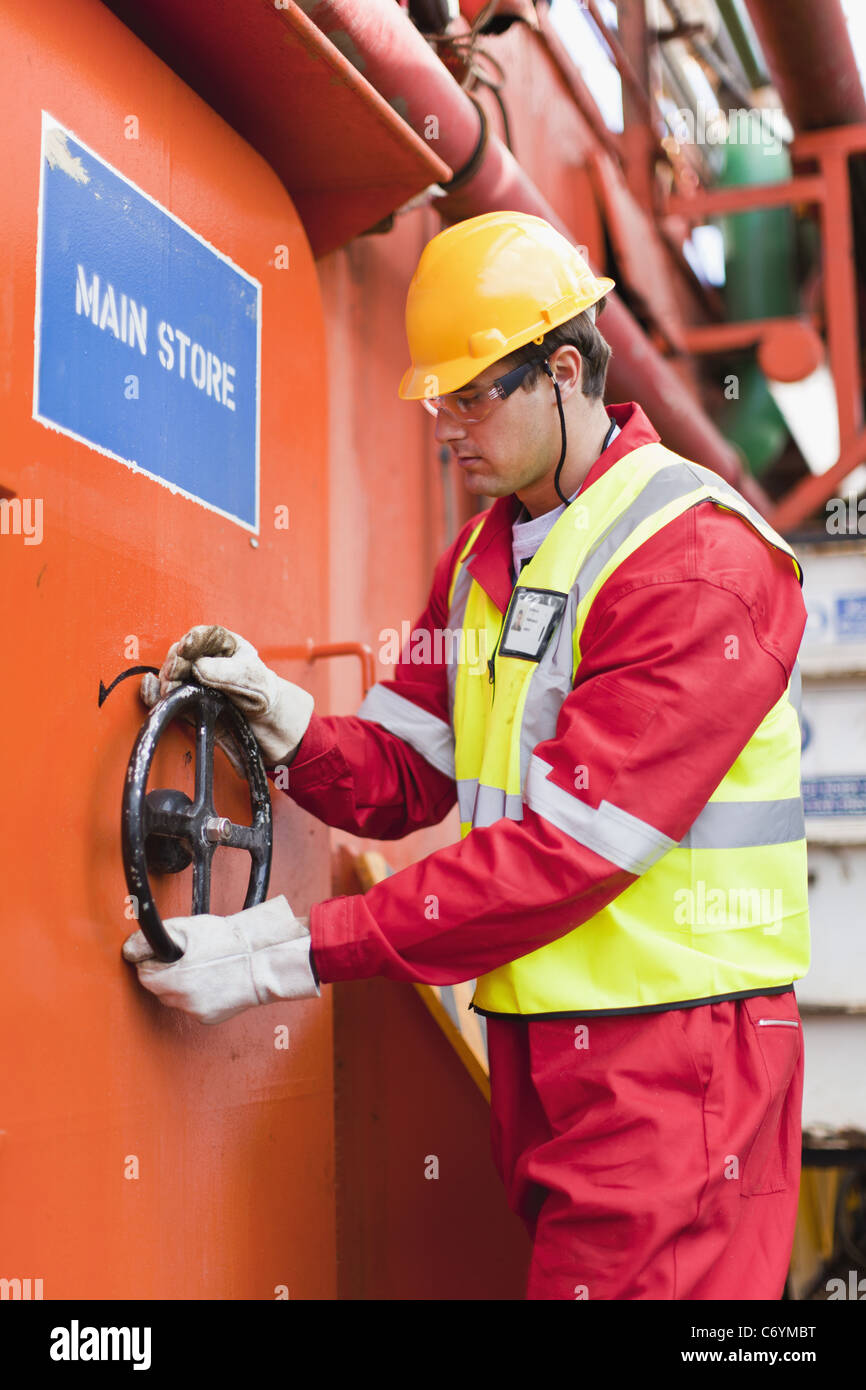 Worker turning wheel on oil rig Stock Photo - Alamy
