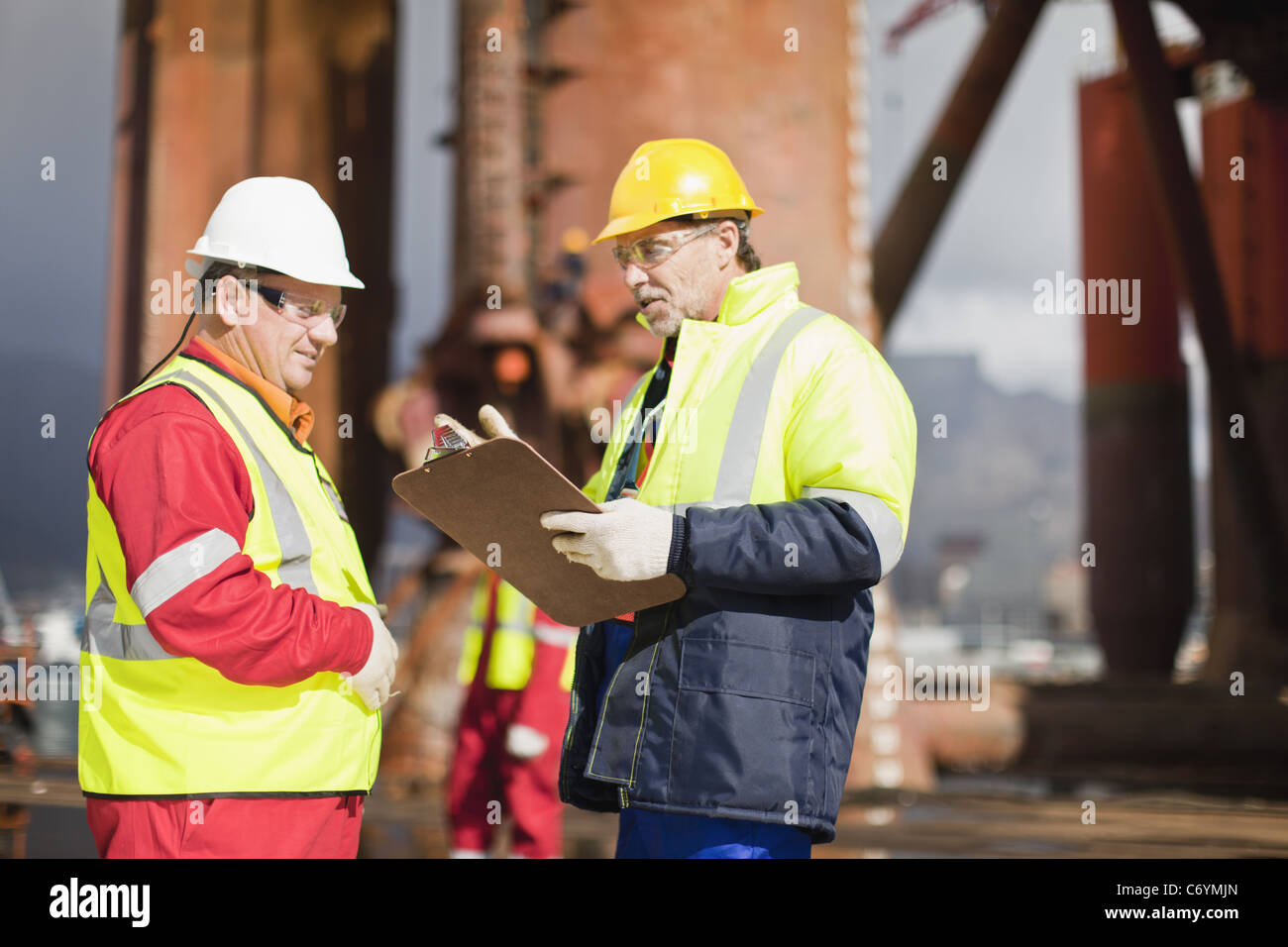 Workers talking on oil rig Stock Photo - Alamy