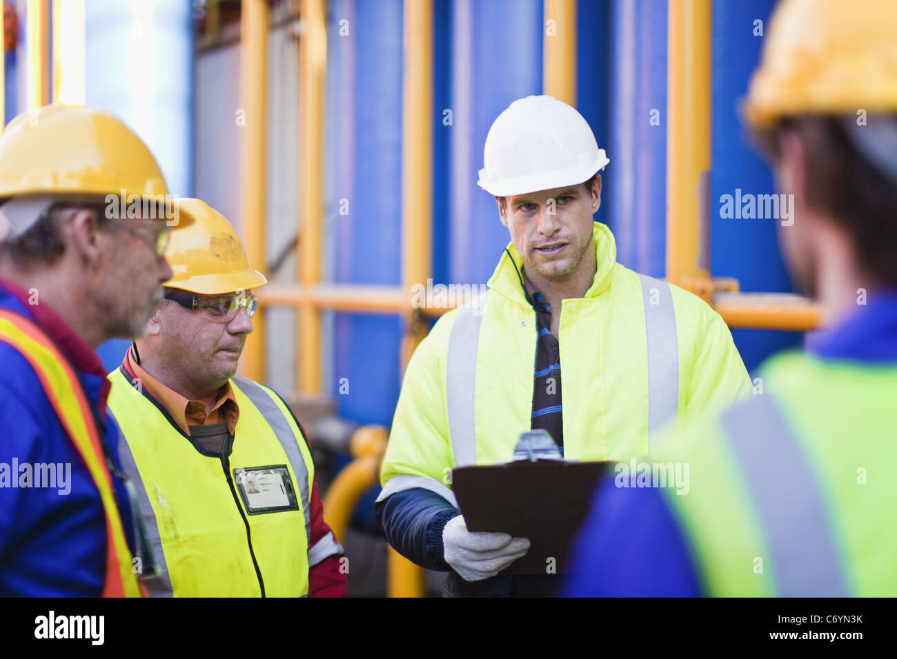 Workers talking on oil rig Stock Photo - Alamy