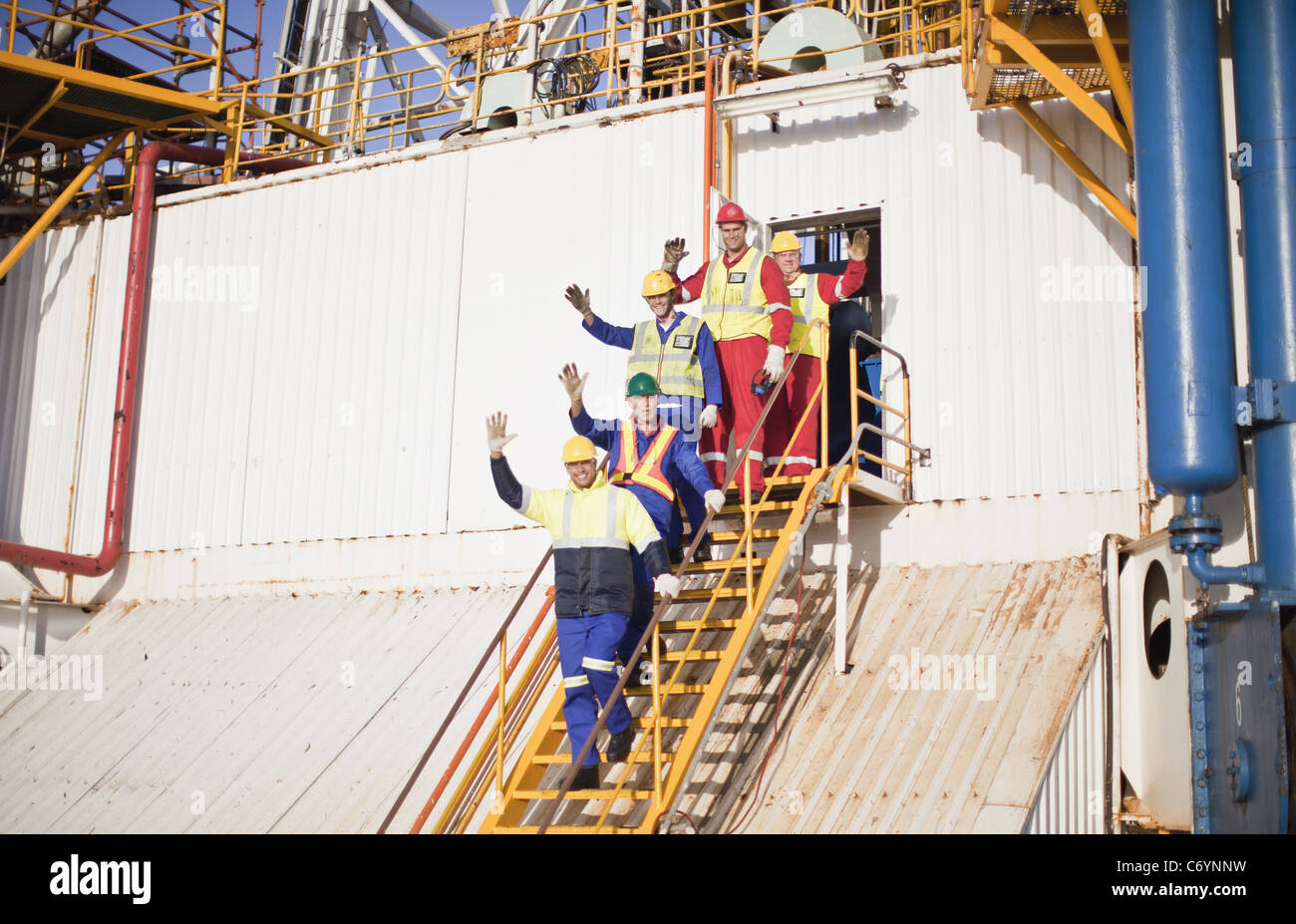 Workers waving from steps of oil rig Stock Photo - Alamy