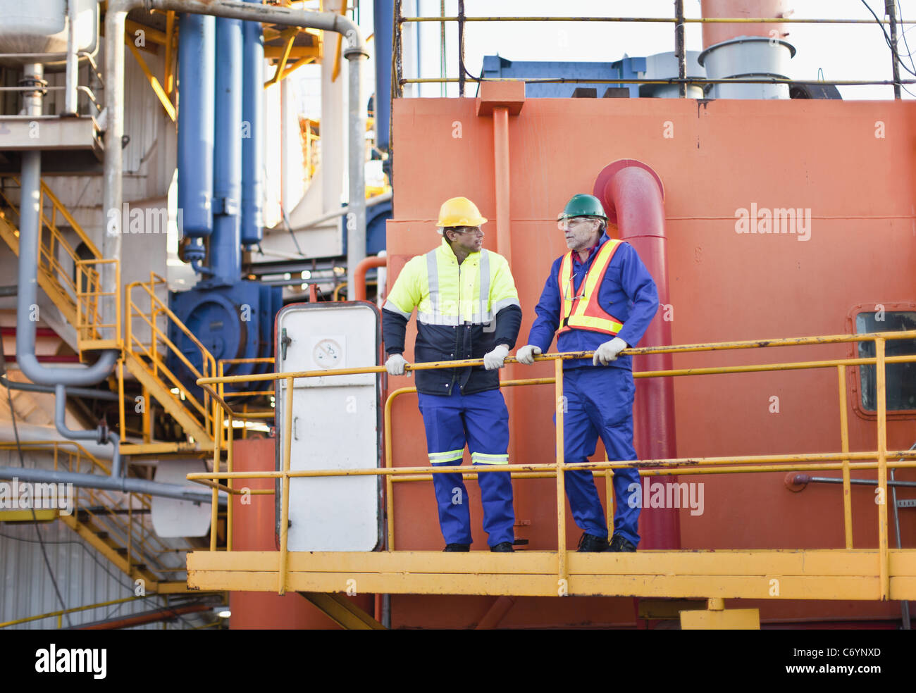 Workers talking on oil rig Stock Photo - Alamy