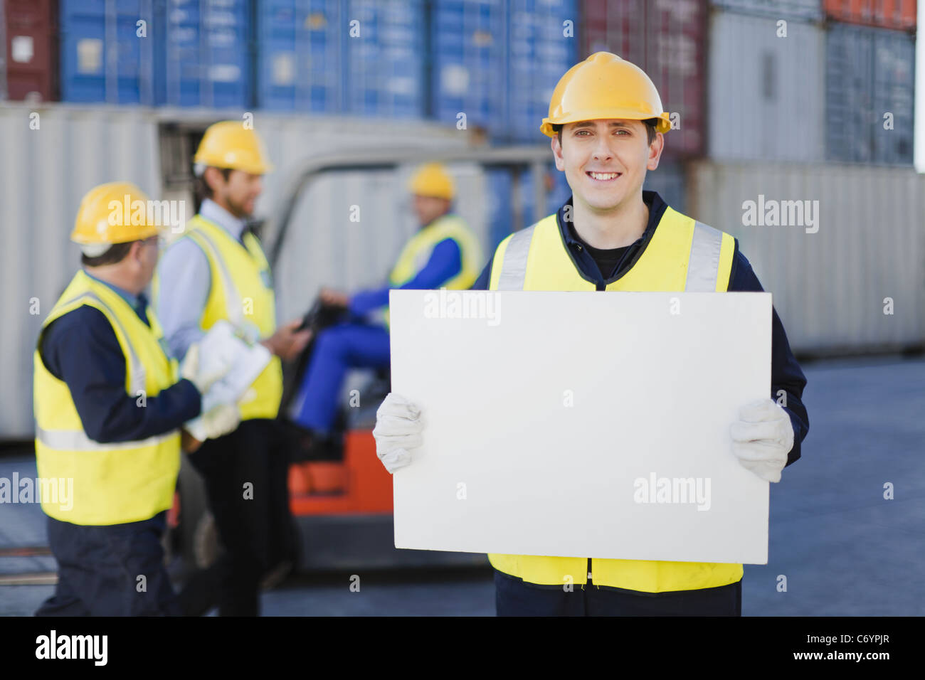 Worker holding sheet in shipping yard Stock Photo - Alamy