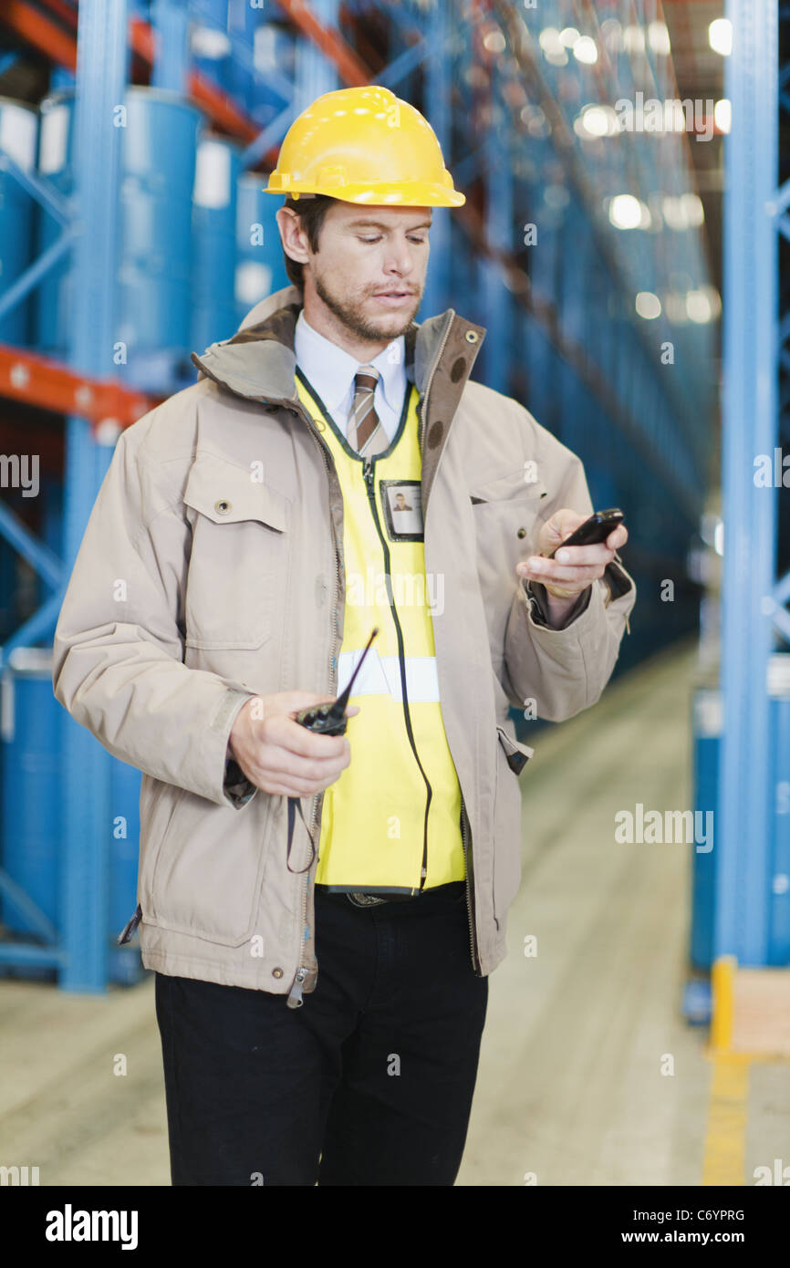 Worker using cell phone in warehouse Stock Photo - Alamy