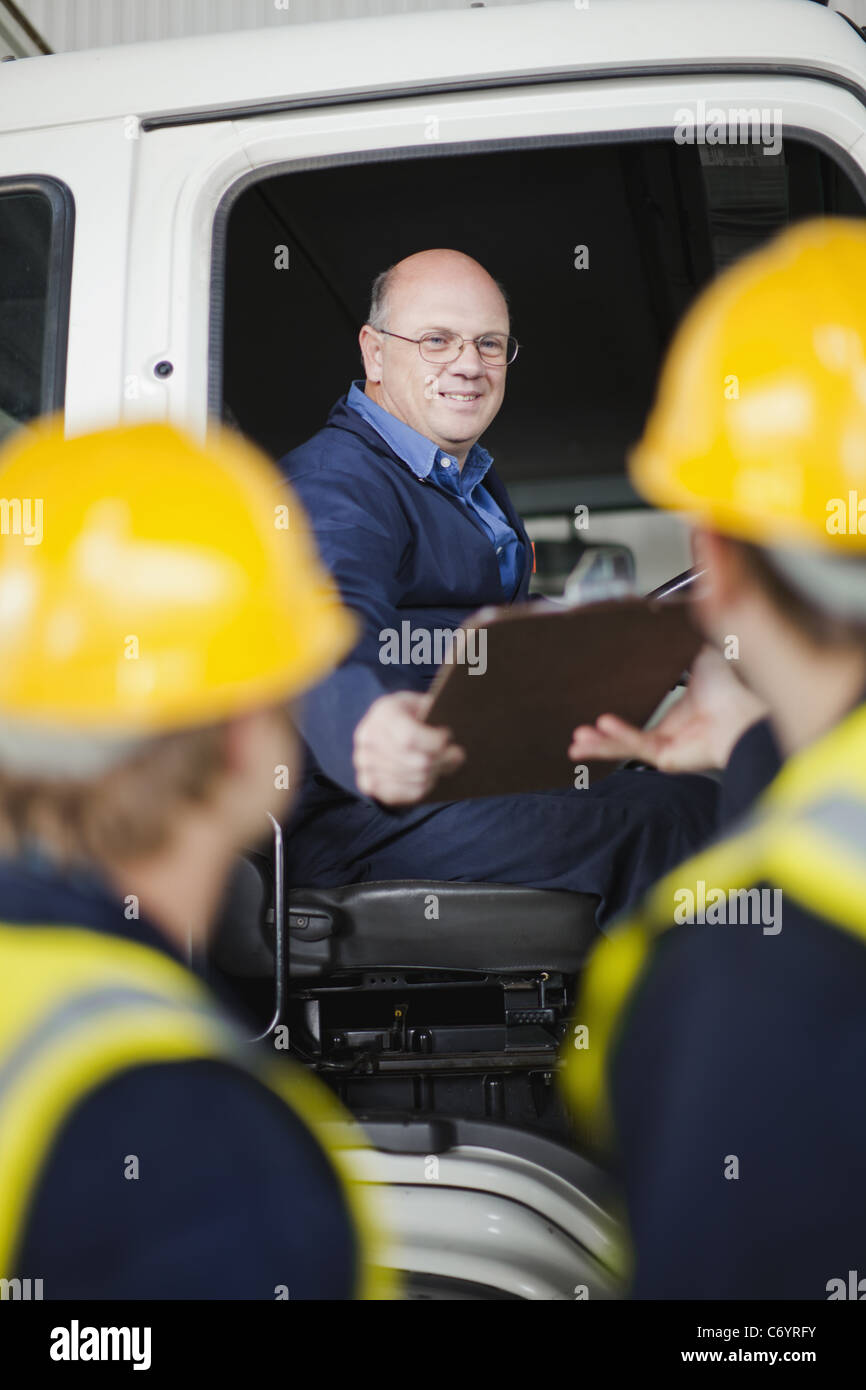 Driver handing clipboard to workers Stock Photo - Alamy