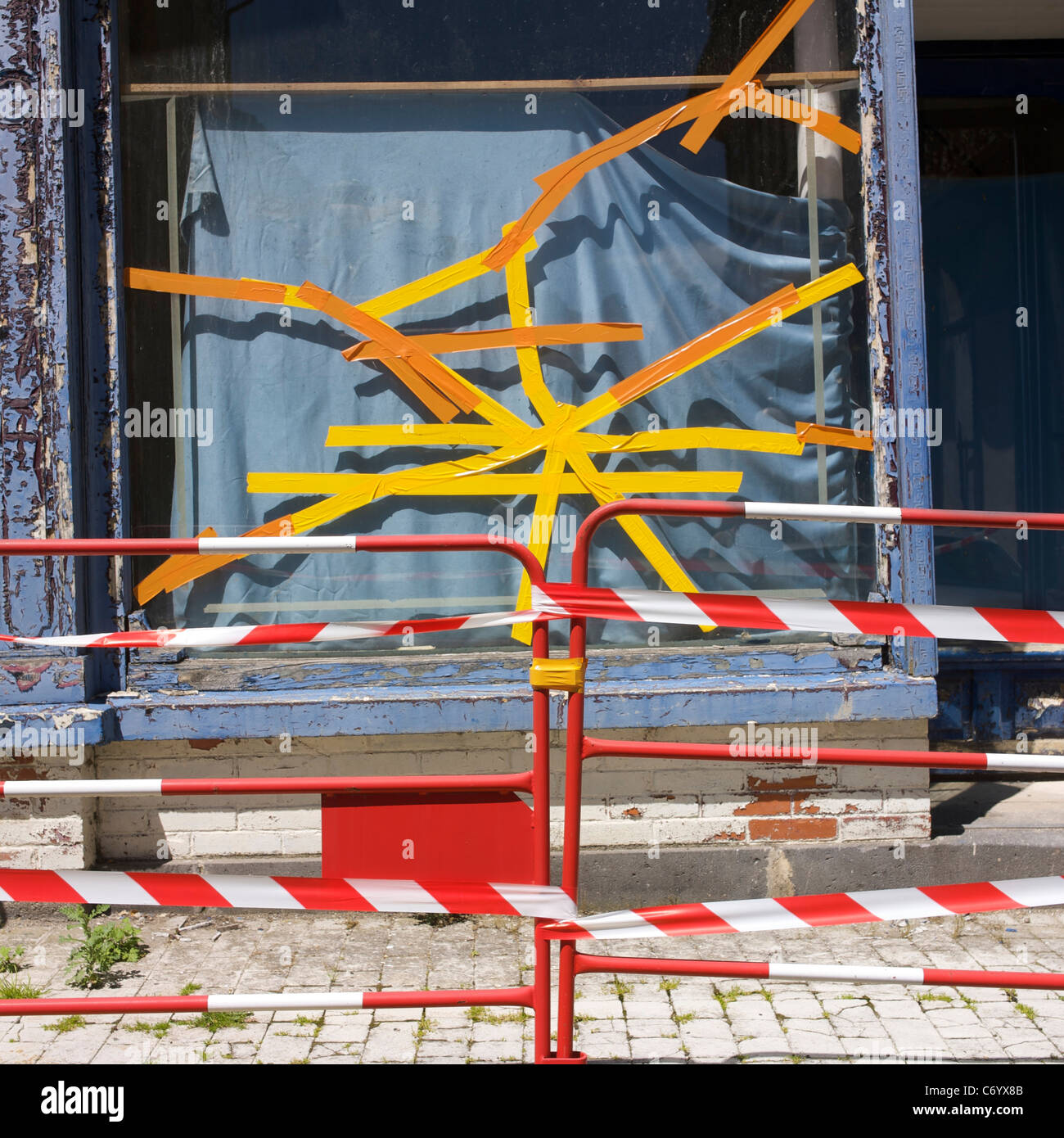 Broken window shop displays safety tape and construction barricade in ...
