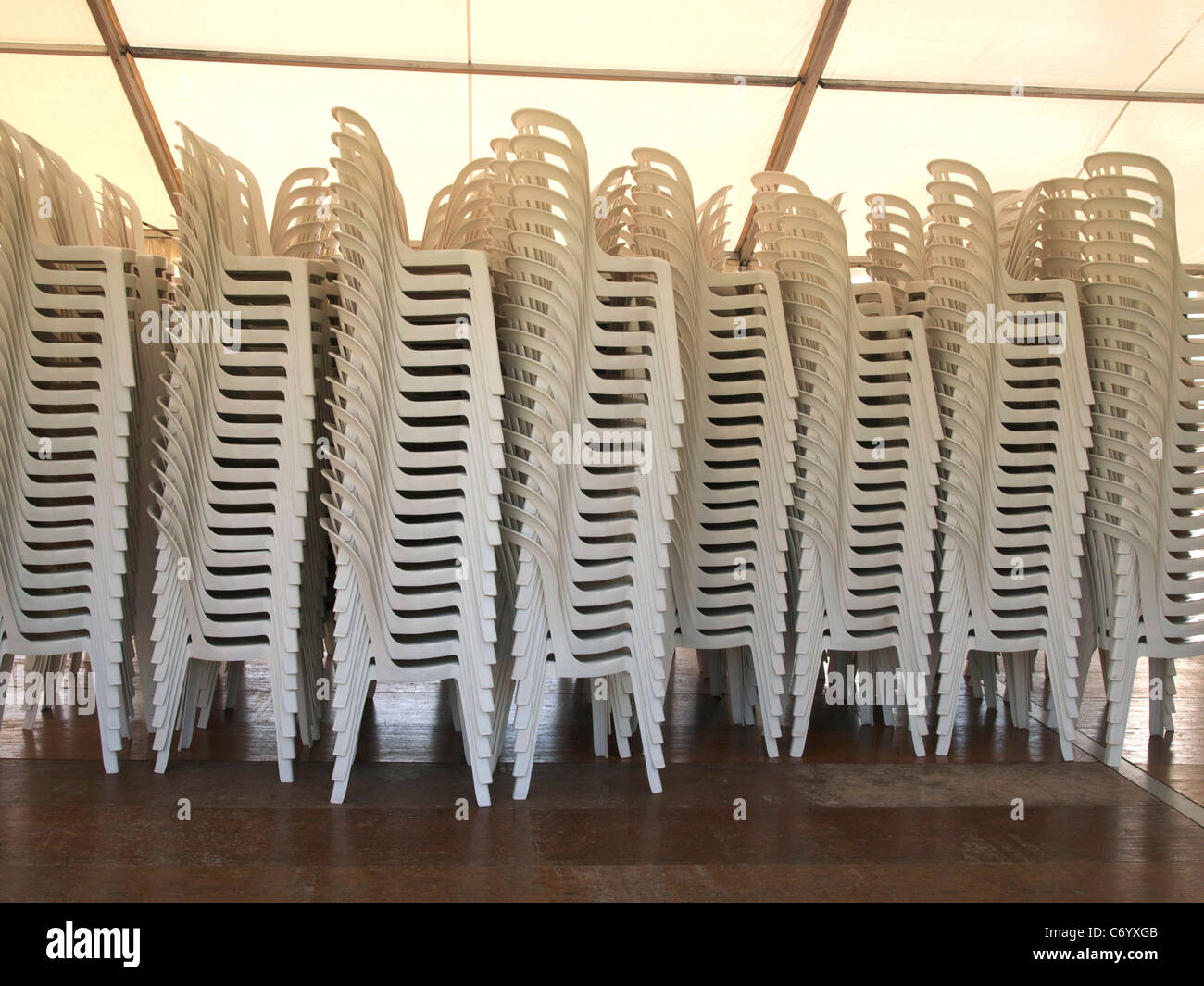 Stacked white plastic chairs arranged in an indoor event space for ...