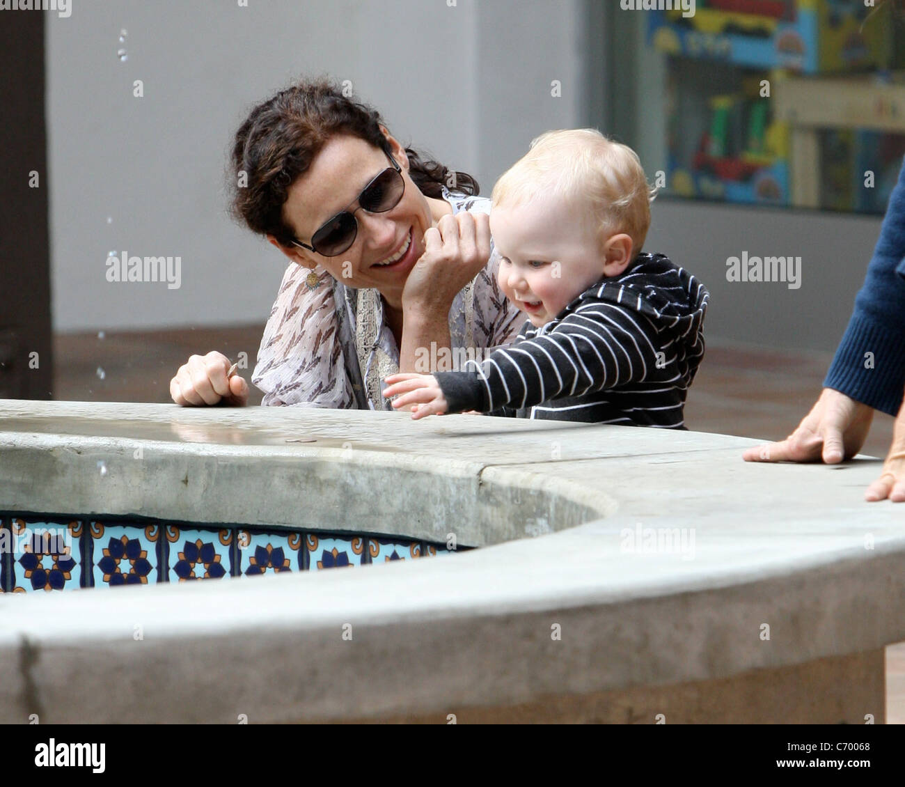 Minnie Driver and Henry Driver throwing coins into a wishing well at ...
