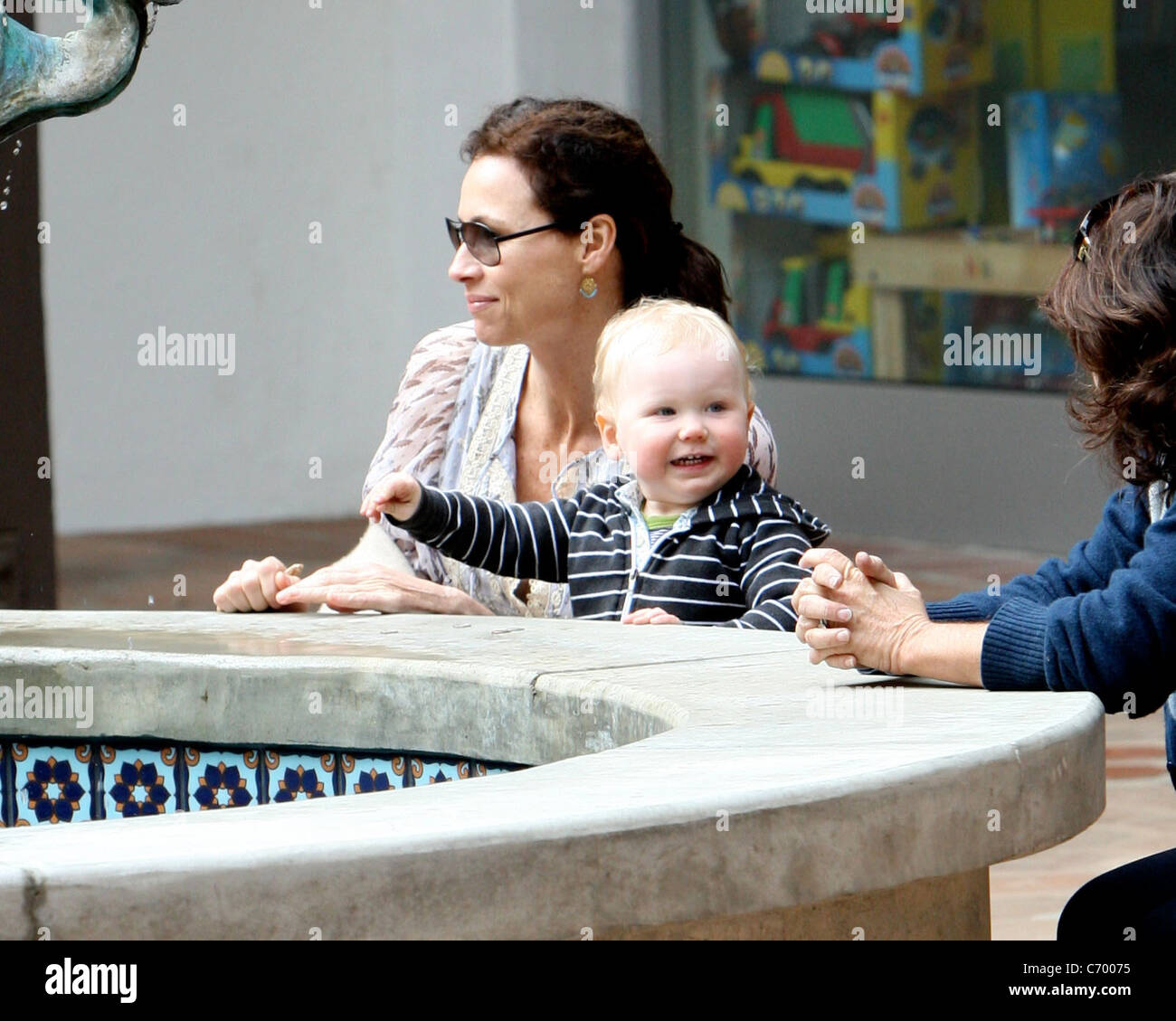 Minnie Driver and Henry Driver throwing coins into a wishing well at ...