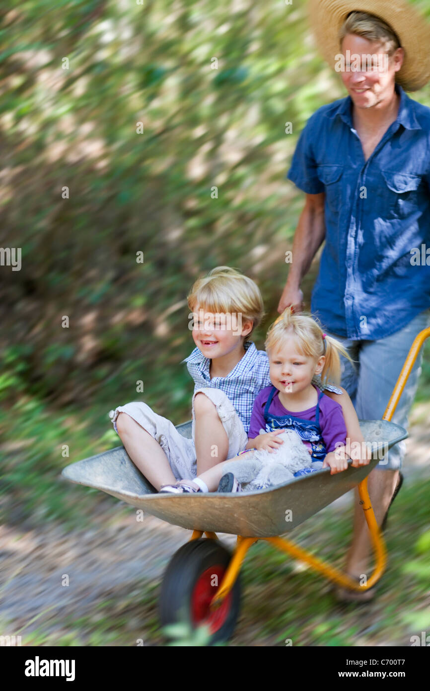 Father pushing children in wheelbarrow Stock Photo - Alamy