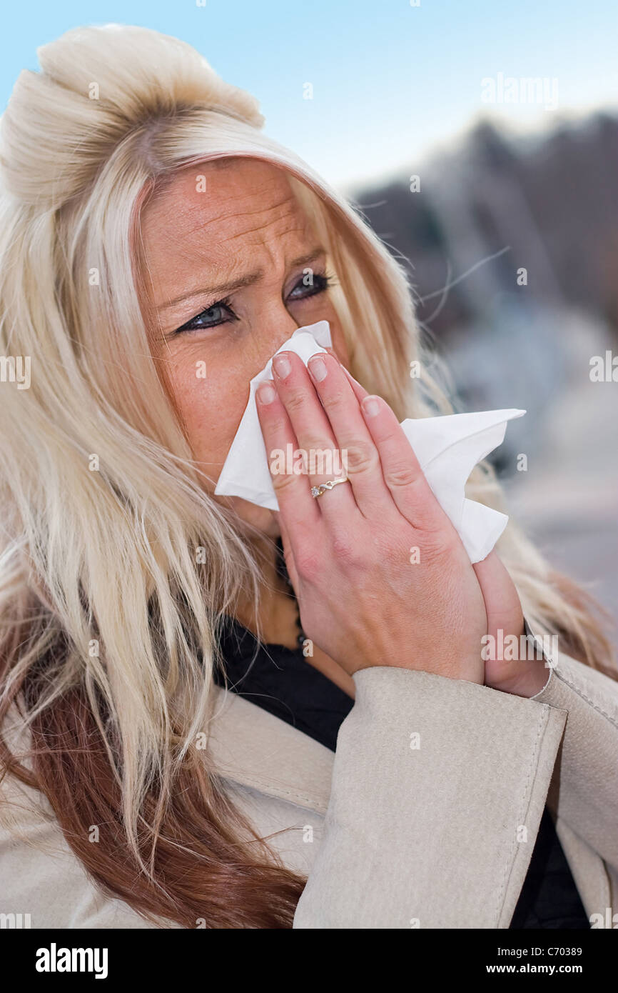 This young woman sneezing into a tissue either has a cold or really bad ...