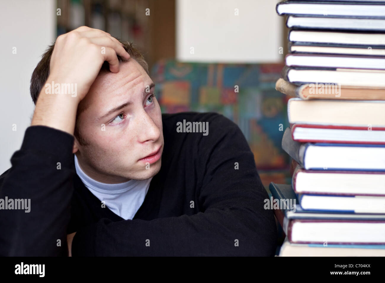 A frustrated and stressed out student looks up at the high pile of ...