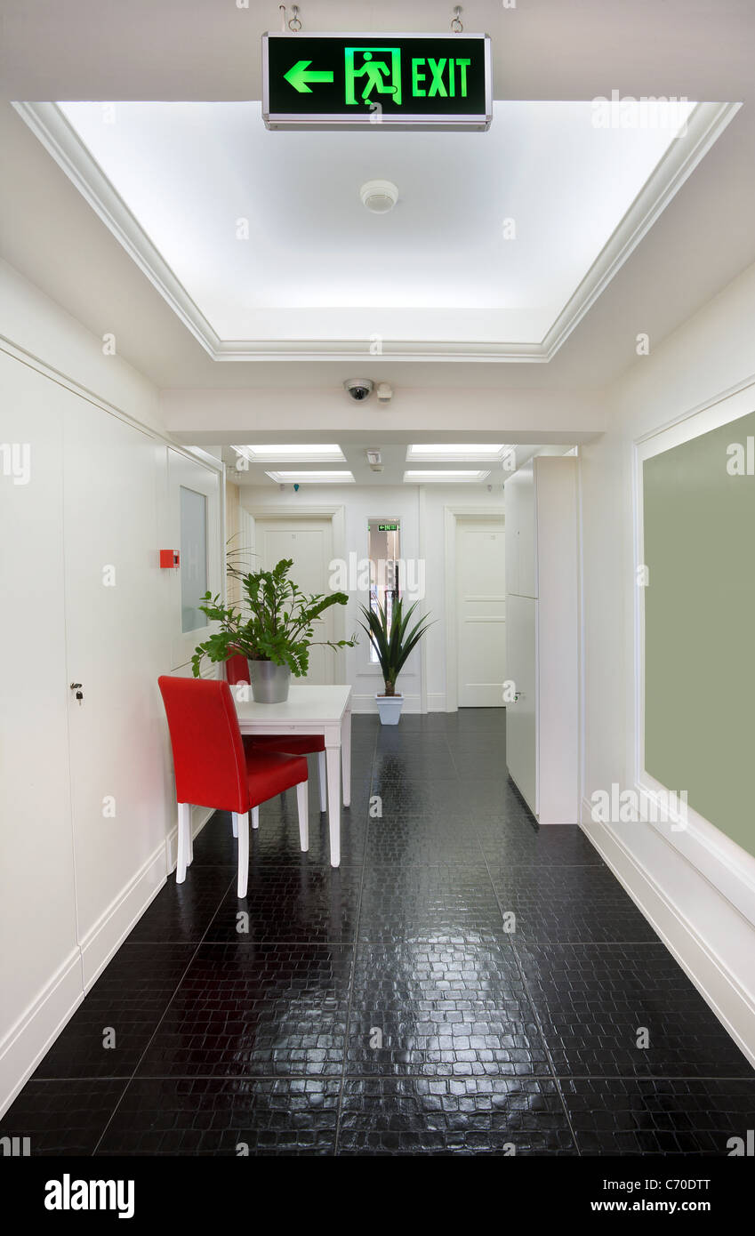 Interior of a hotel halls, with white walls, black floor and exit sign ...
