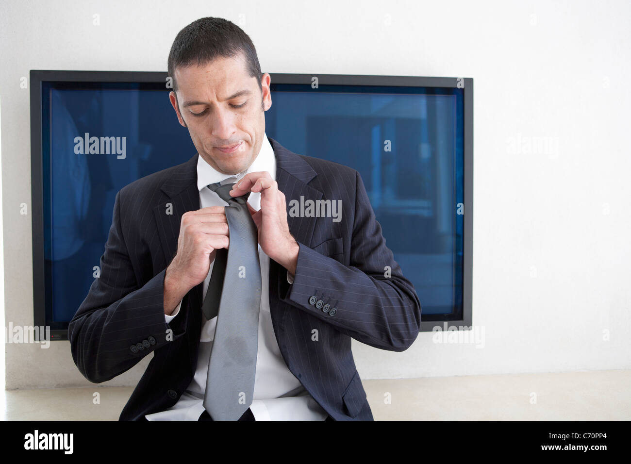Businessman tying his tie in office Stock Photo - Alamy
