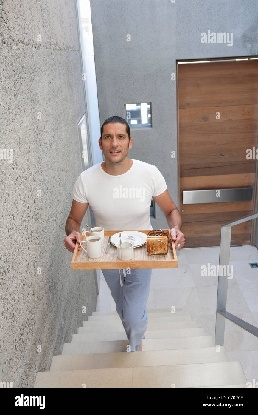 Man carrying tray of food up stairs Stock Photo - Alamy