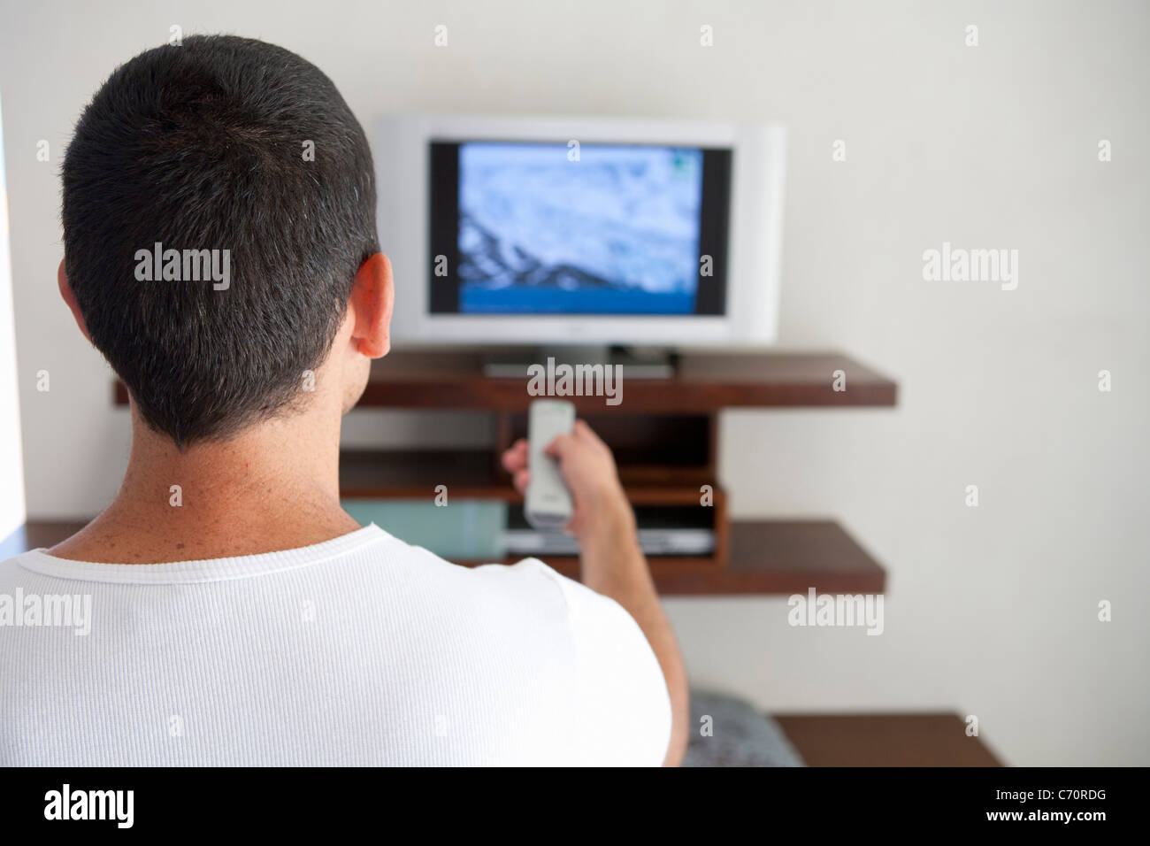 Man watching television in living room Stock Photo - Alamy