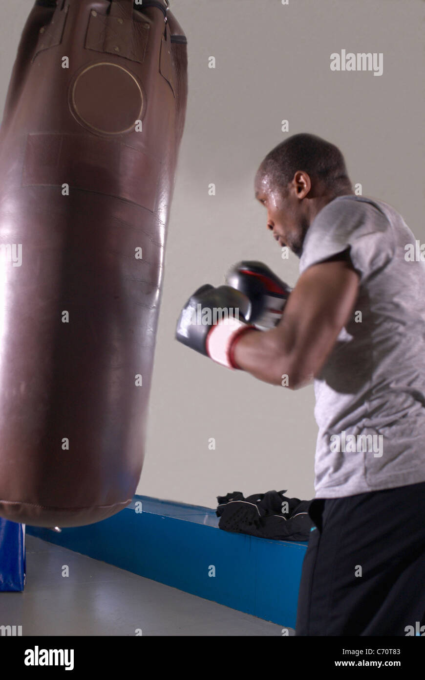 Boxer using punching bag in gym Stock Photo - Alamy