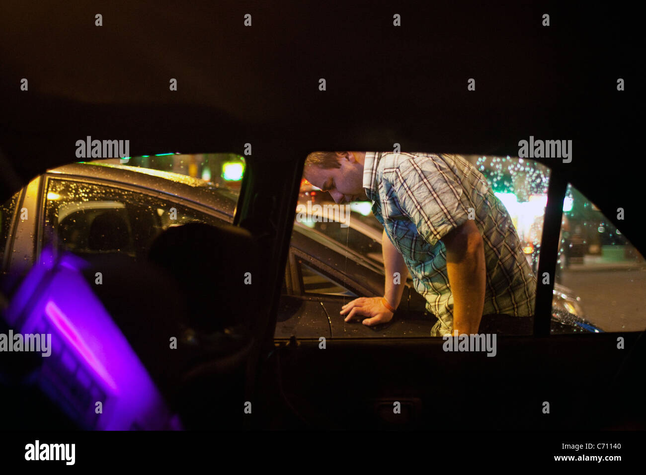 A man throwing up between cars on a night out in Blackpool, England, UK ...