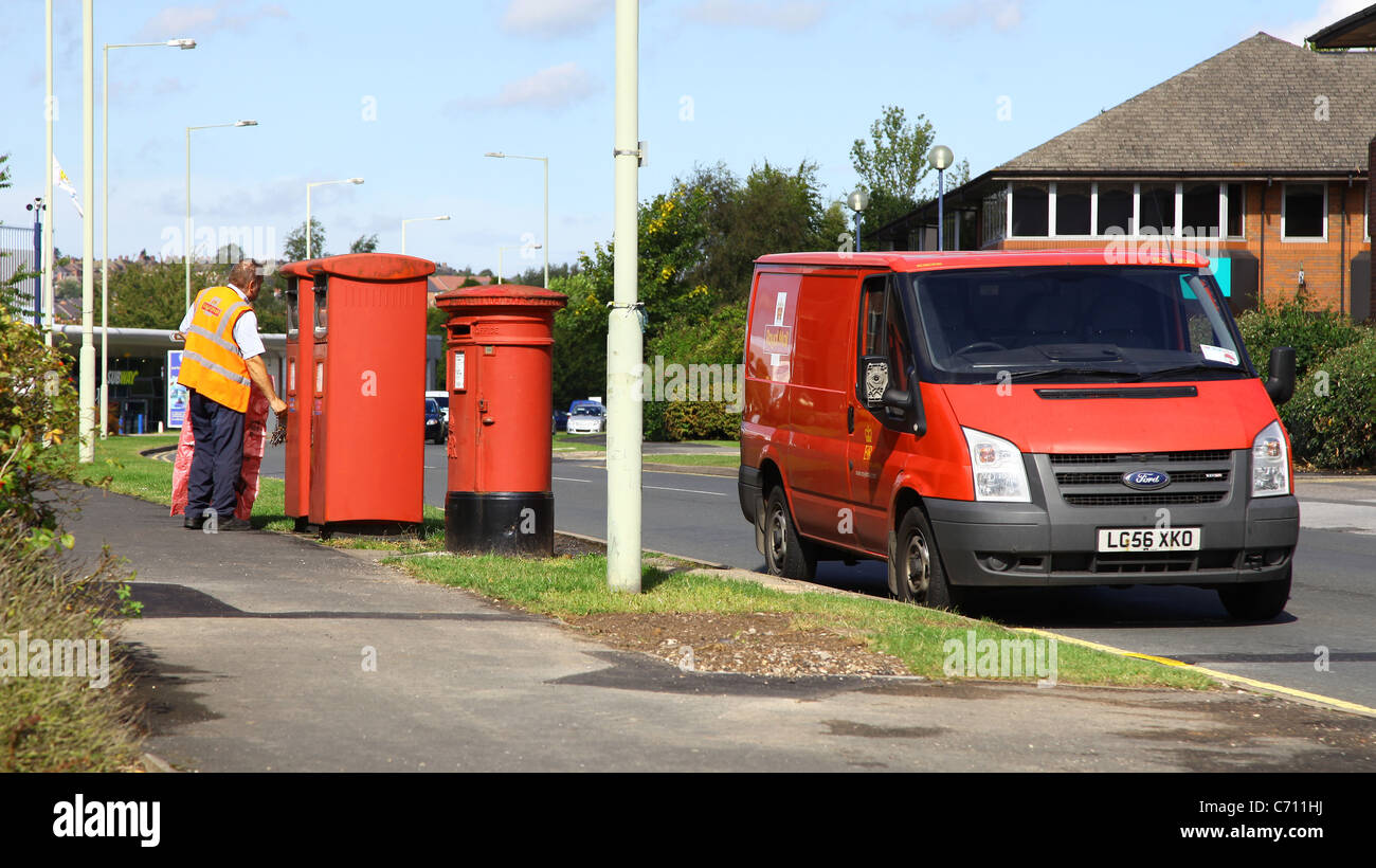 A postman collecting mail from a post box or letter box, England, UK ...