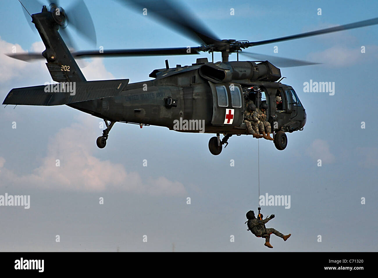A Soldier dangles from a UH-60 Black Hawk helicopter as he is lowered ...