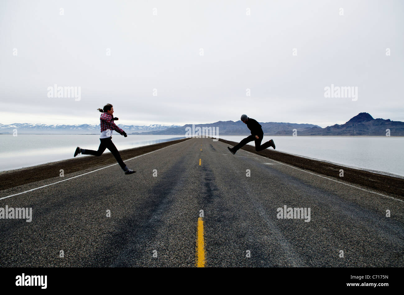 A couple jump on a long and lonesome road in West Wendover, Utah Stock ...