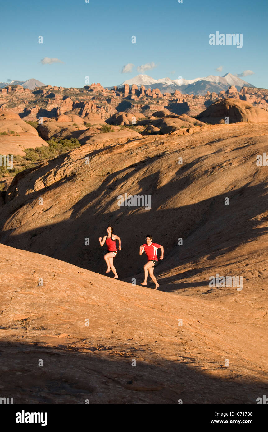 Man and woman barefoot running on sandstone above the Colorado River ...