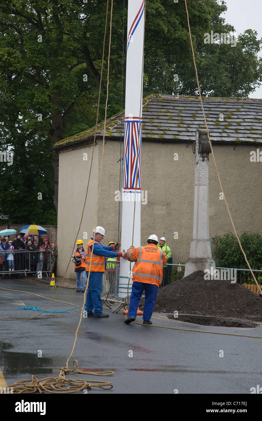 The newly decorated Maypole being put back into position at the center ...