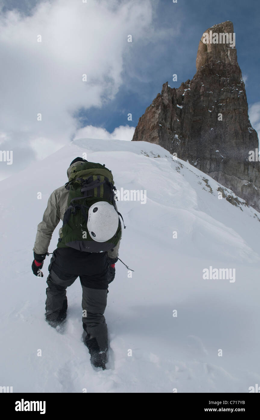 Man hiking along snowy ridgeline below rock spire, Telluride, Colorado ...