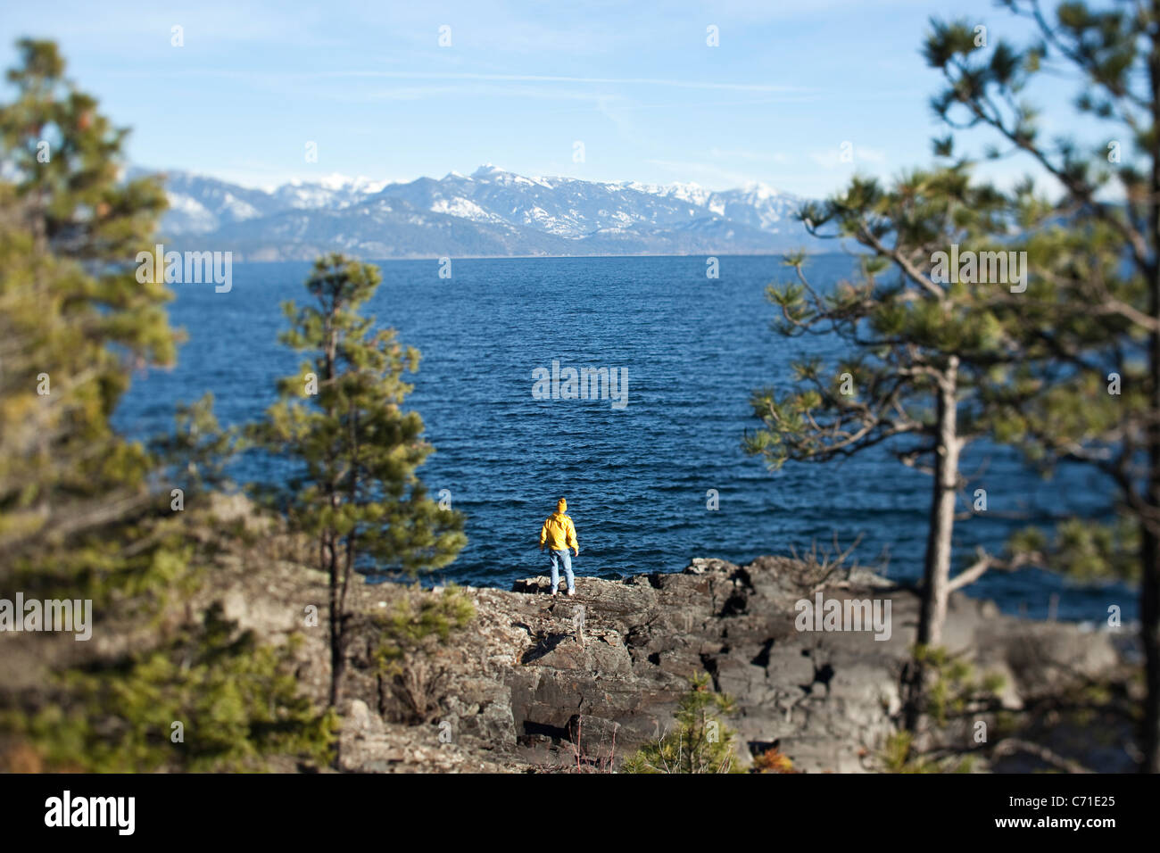 A athletic retired man stands at the edge of a cliff overlooking a ...