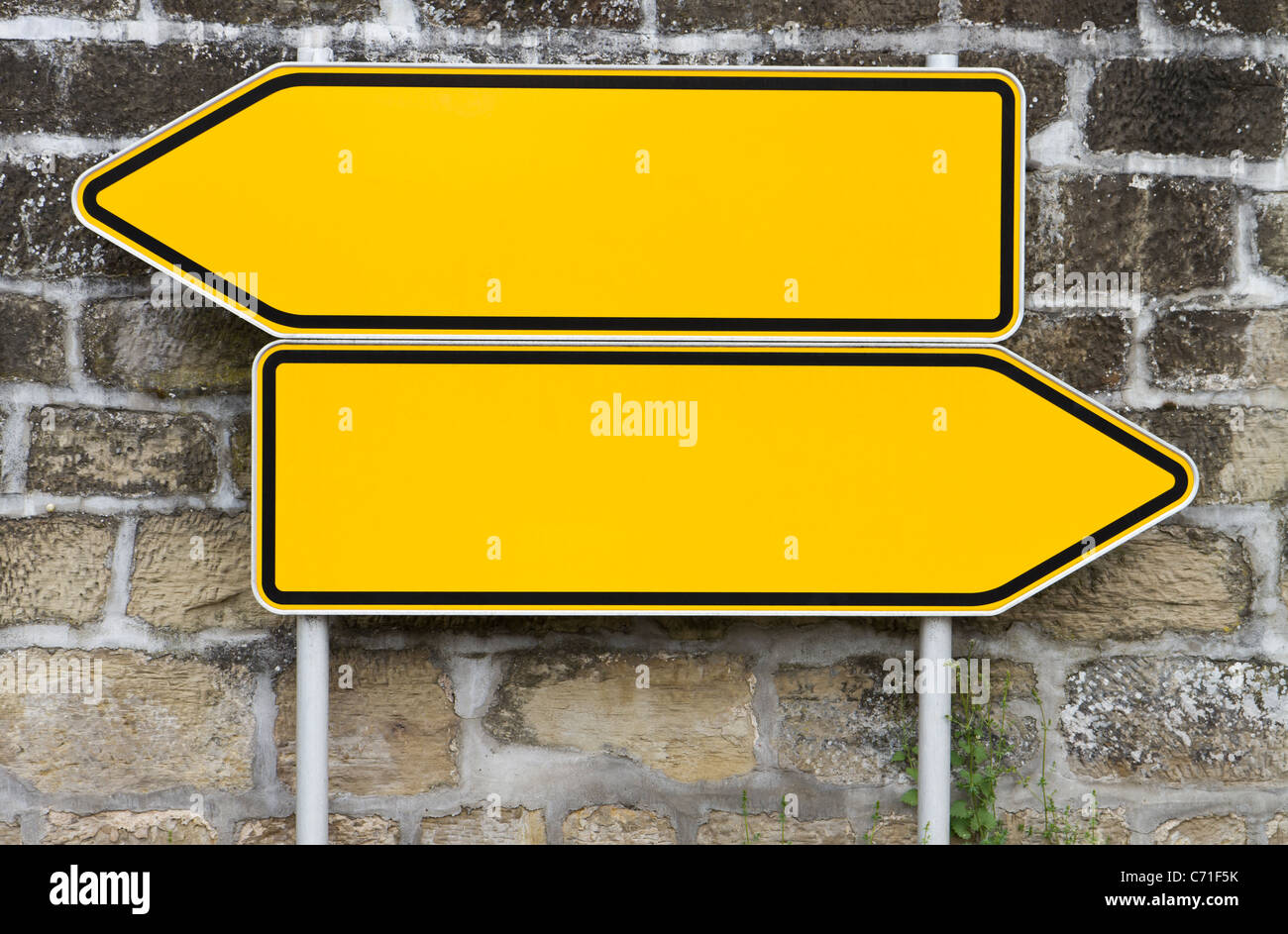 direction signs with wall in background. yellow signs. arrow shape ...