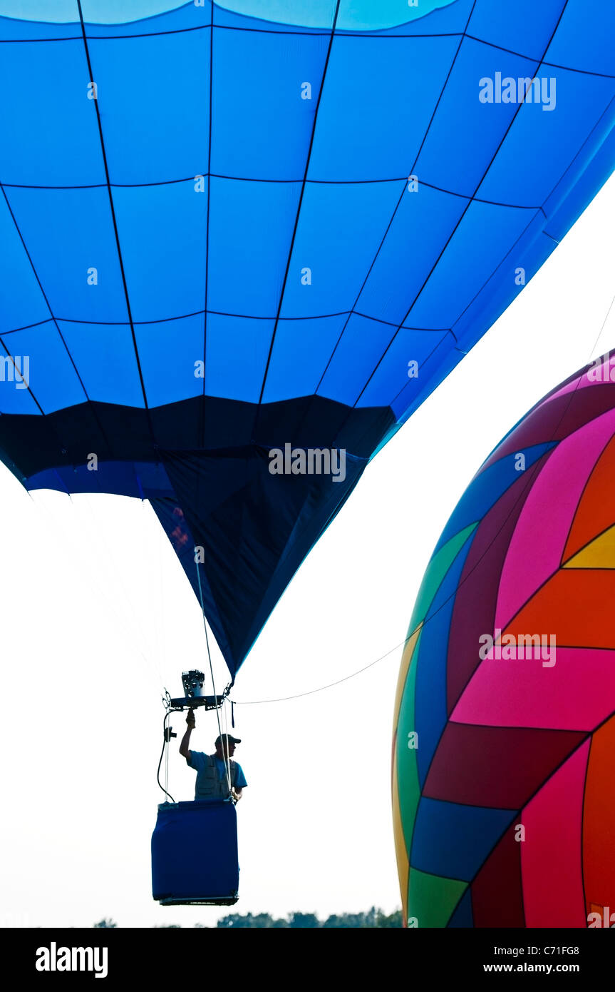 One man hot air balloon rising with pilot silhouetted against a bright ...