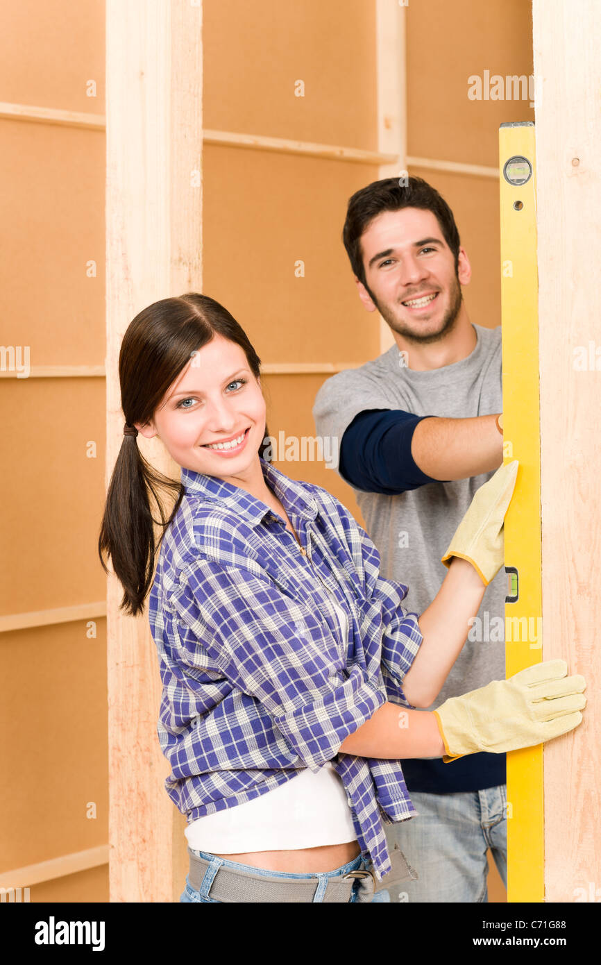 Home improvement smiling young couple fixing wall with spirit level ...