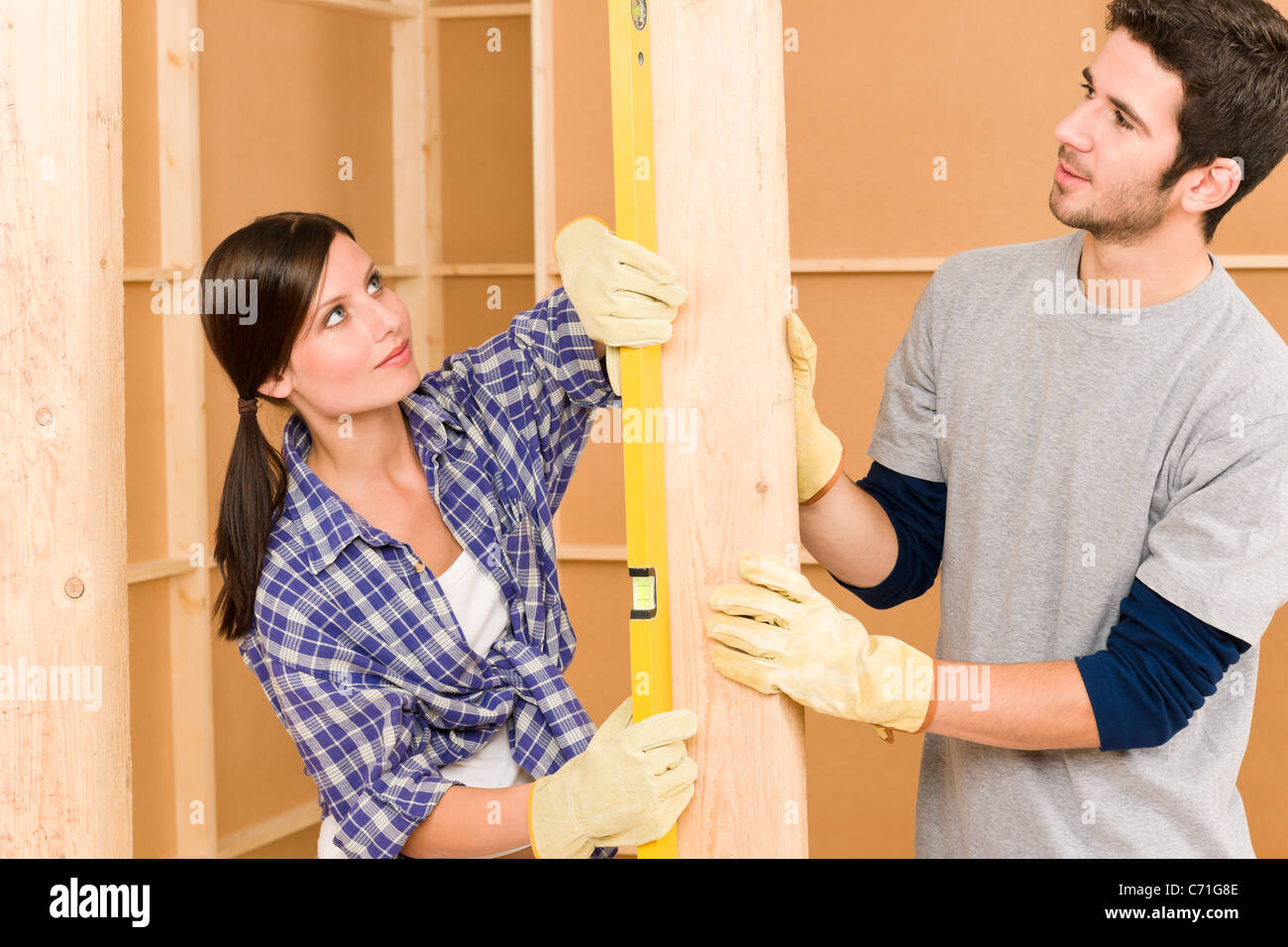 Home improvement smiling young couple fixing wall with spirit level ...