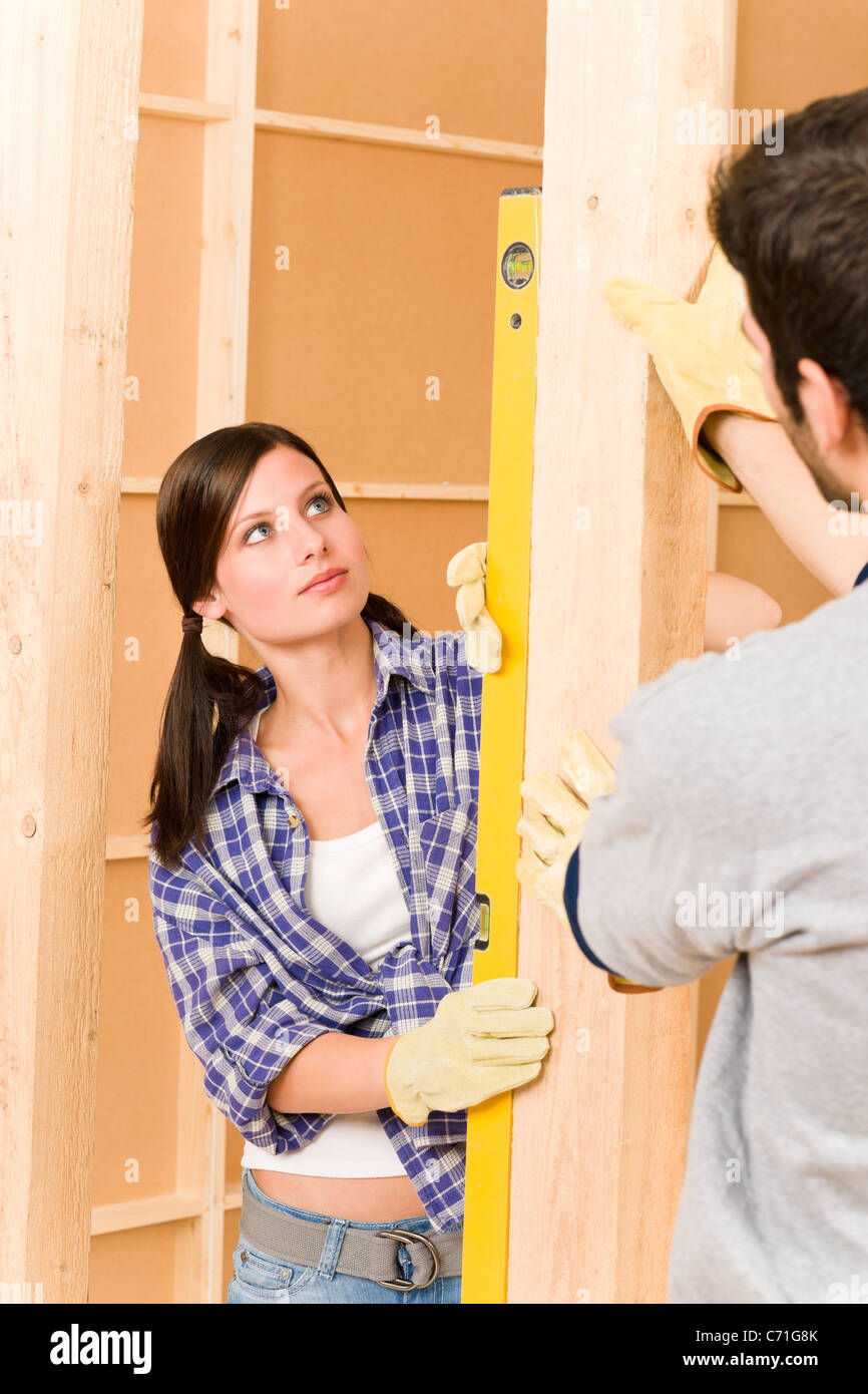 Home improvement smiling young couple fixing wall with spirit level ...