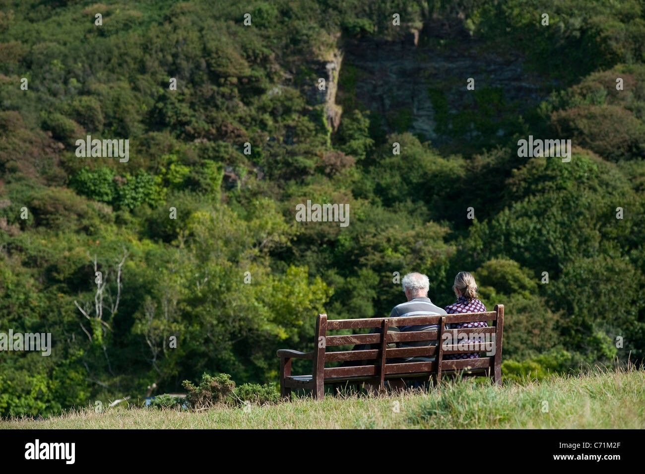 Couple sitting on a bench admiring the beautiful cornish countryside in ...